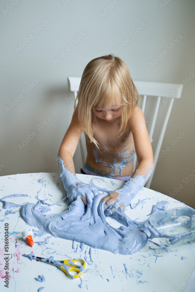Shirtless girl playing with slime at table Stock Photo | Adobe Stock