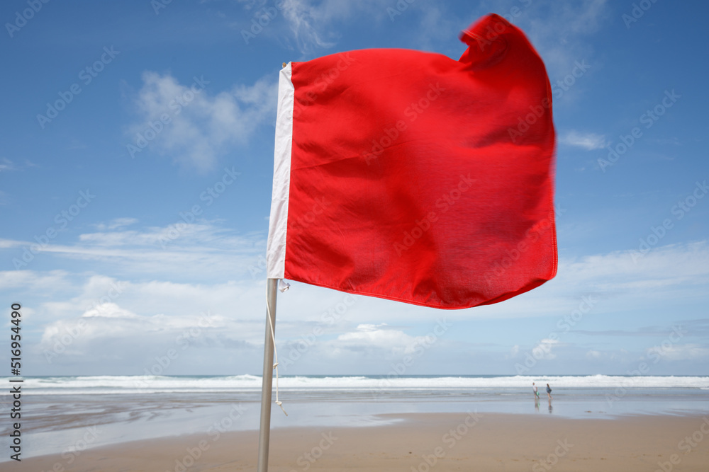 Red flag on the Beach. A red flag flies in the wind on a windy but ...