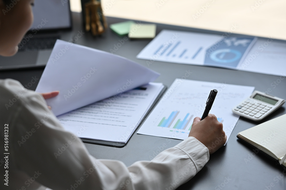Back view on Businesswoman's hand pointing on her report, checking ...