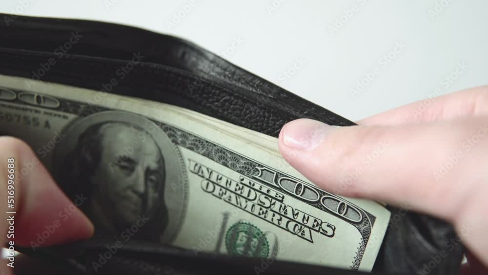 A man shows a 100 dollar bill inside his wallet. The concept of savings ...