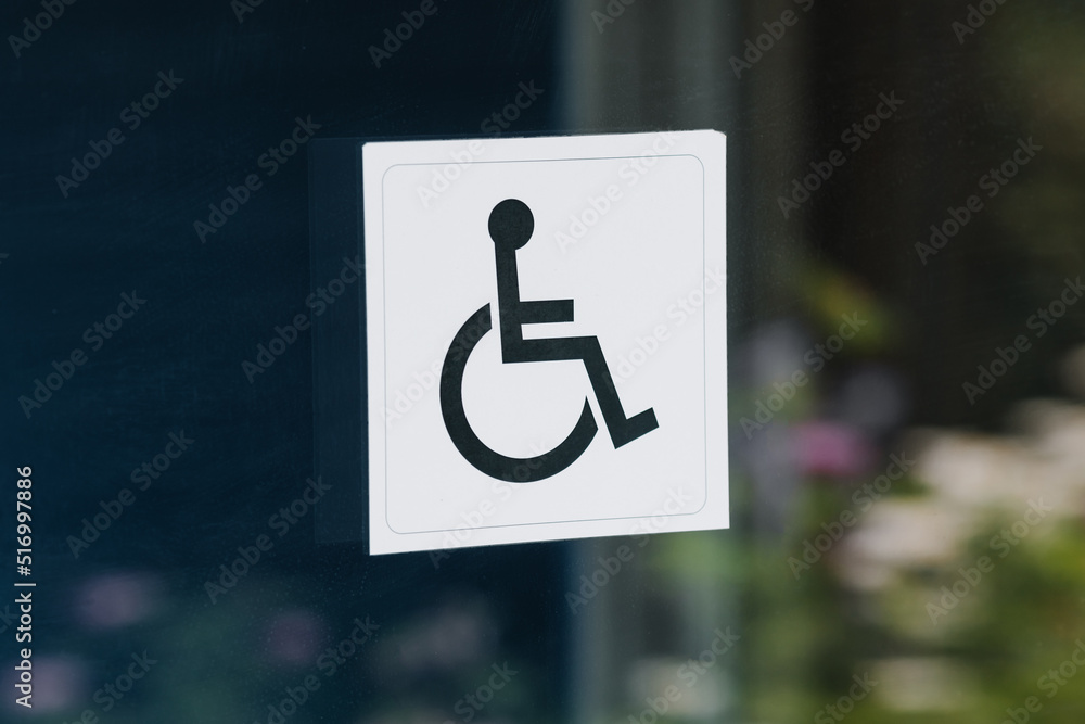 Black sign for people with disabilities in a wheelchair on a glass door ...