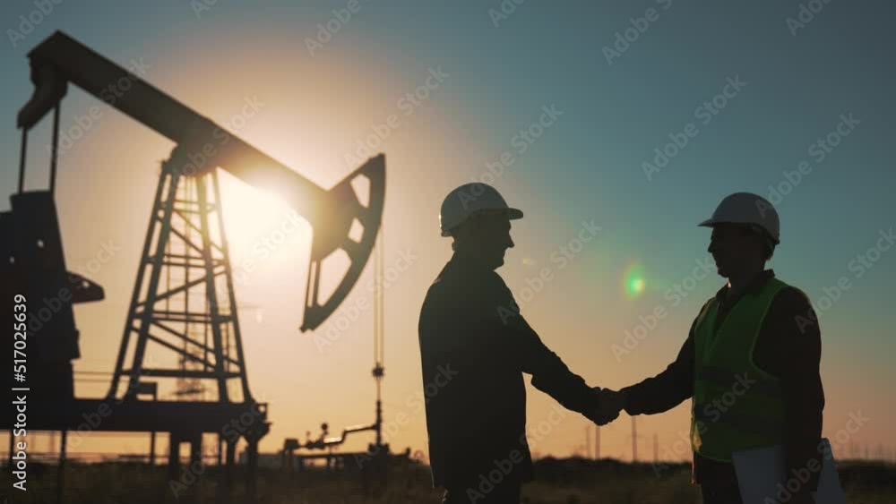 Oil pump. Engineers handshake. Corporate contract. People in helmets ...