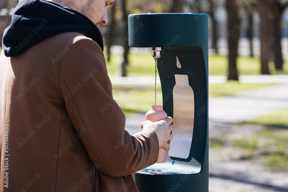 Foto de Man refilling his water bottle at the city. Free public water ...