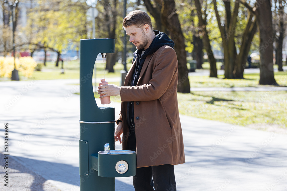 Man refilling his water bottle at the city. Free public water bottle ...