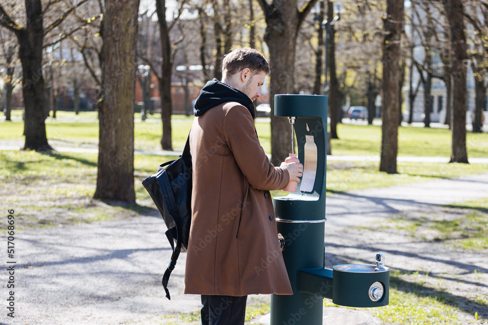 Man refilling his water bottle at the city. Free public water bottle ...