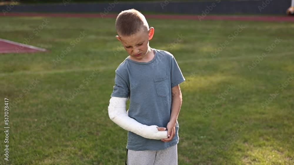 sad little boy with a fractured limb outdoors on summer day. a child's ...