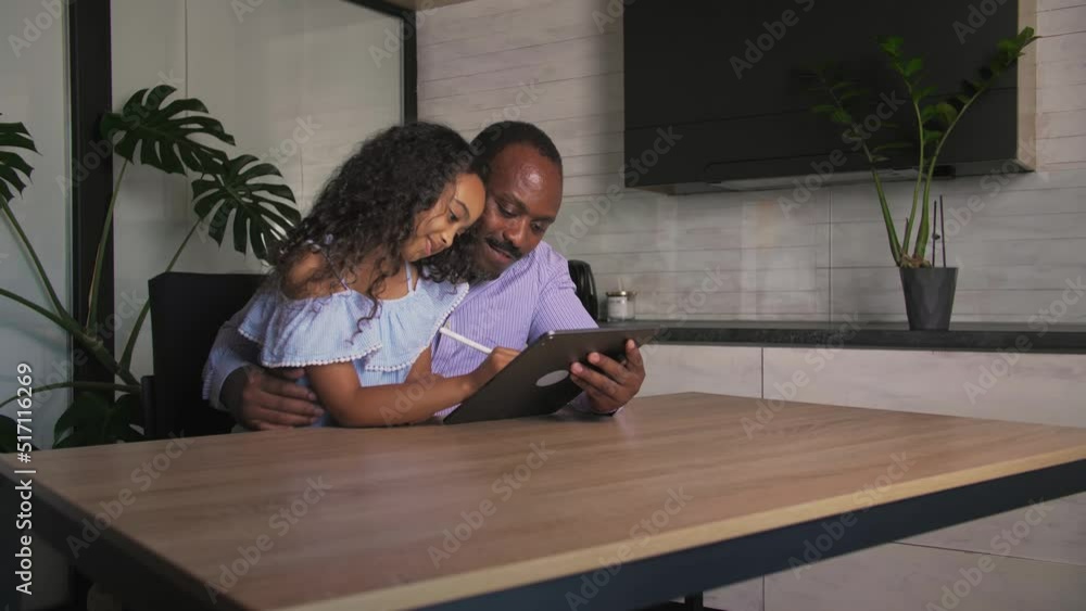 Vidéo Stock Smiling African man teaches his daughter how to draw on a ...