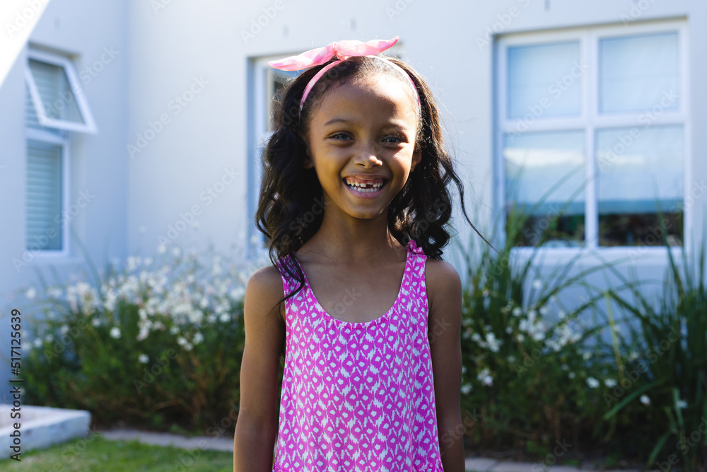 Portrait of biracial girl with missing tooth smiling while standing ...