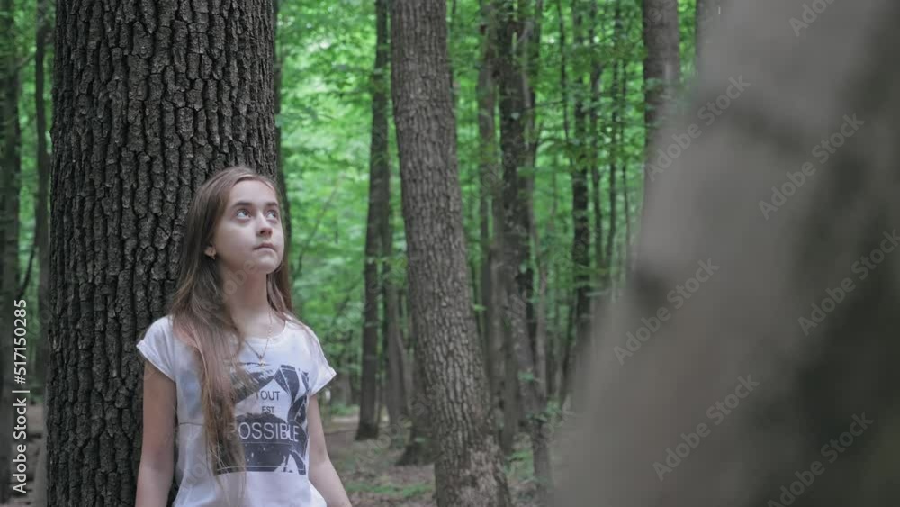 A teenage girl walks herself in the forest. A cute girl in gray jeans ...