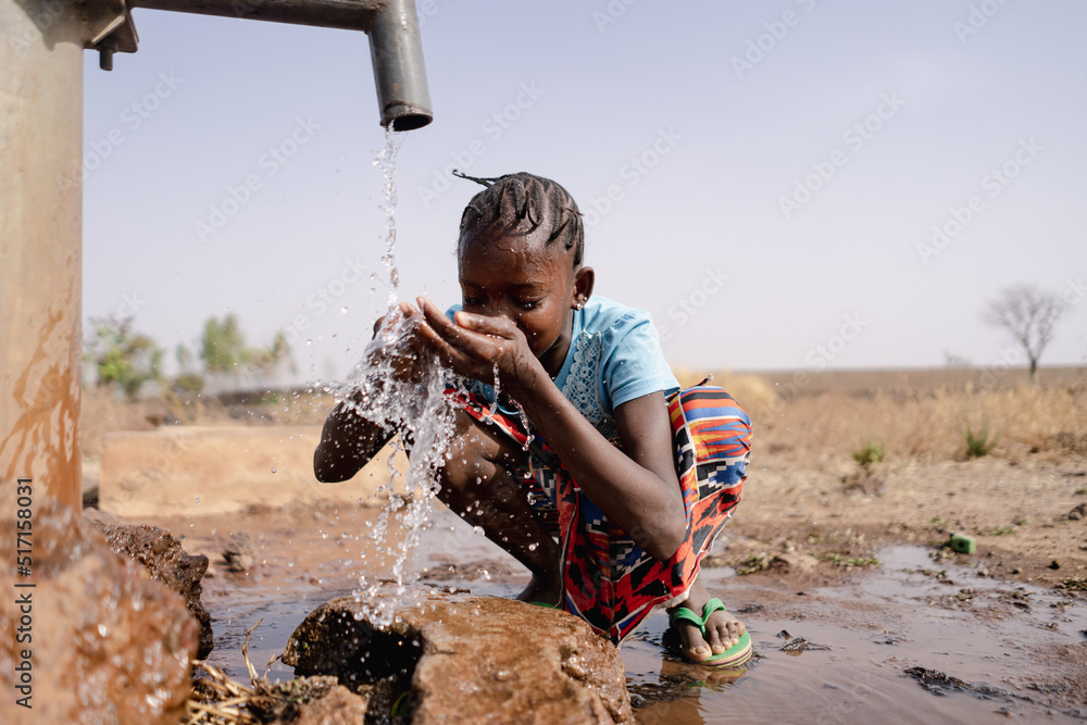 Little African girl splashing herself with copious amounts of clean ...