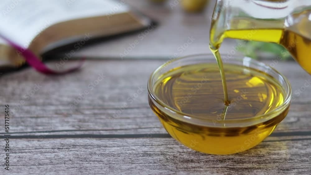 Hand holding glass jar and pouring out pure virgin olive oil into a ...