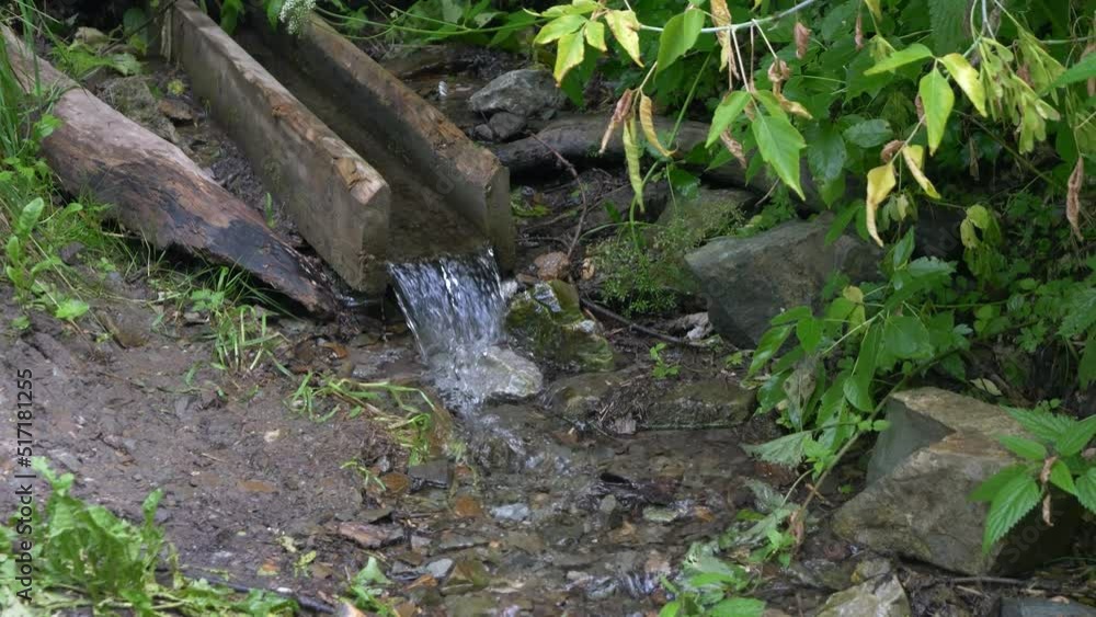 Spring water flows through a tray and overflows into a stream Stock ビデオ ...