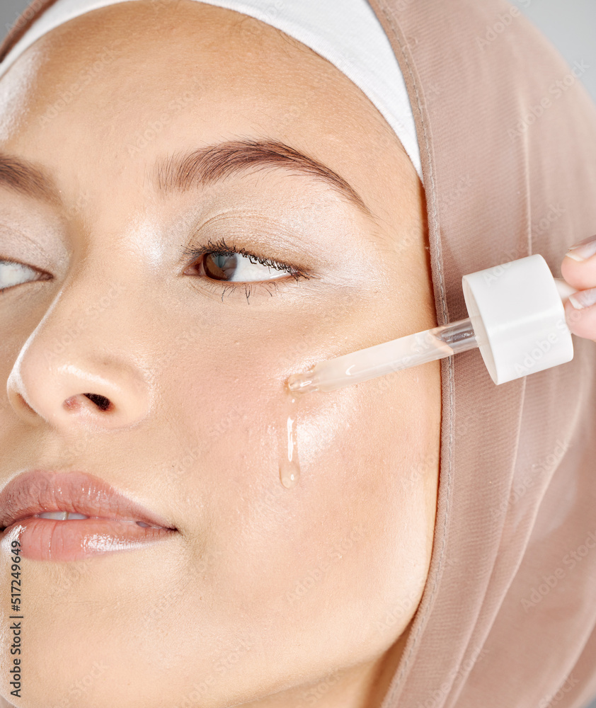 A young woman applying antiaging facial serum to her face and skin ...