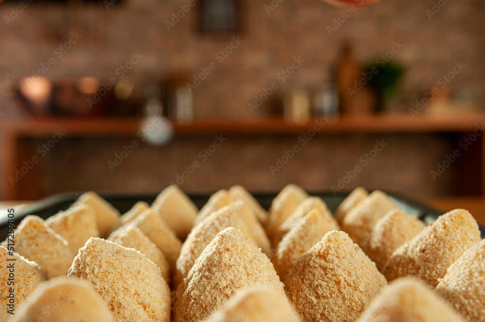 Breading brazilian croquette (coxinha de frango) on kitchen bricks wall ...