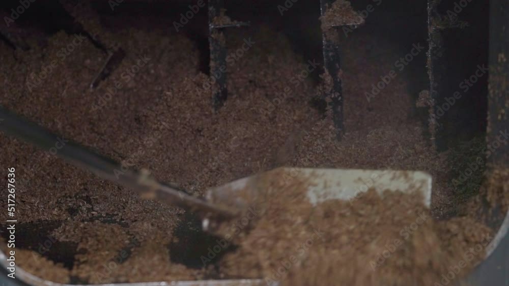 Lots of spent grain collected in the factory tank. Worker cleans the ...