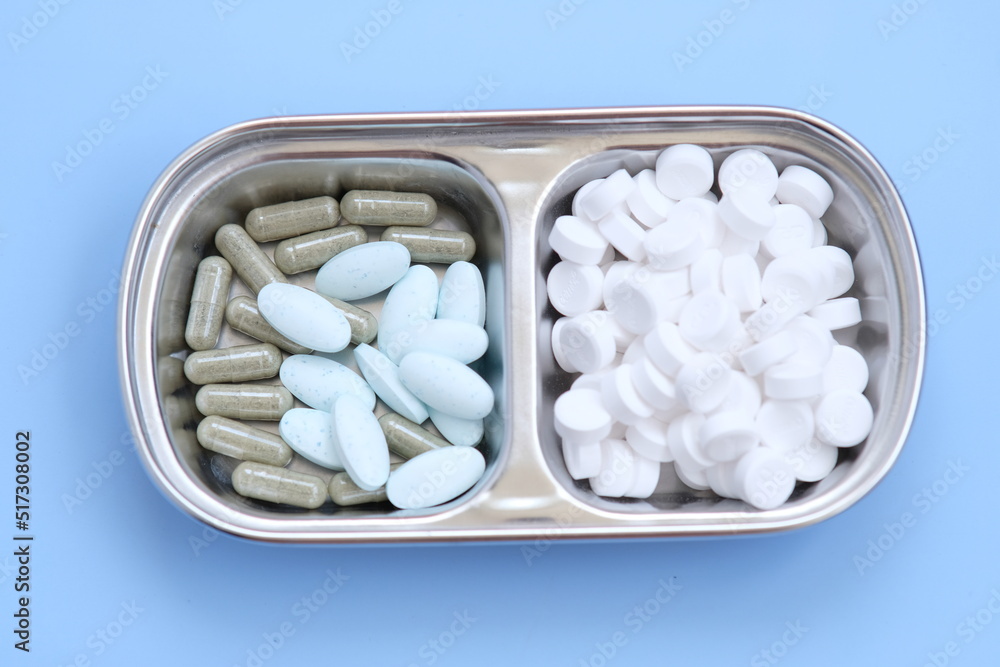 Variety of Tablets, pills, and capsules are scattered across a blue ...