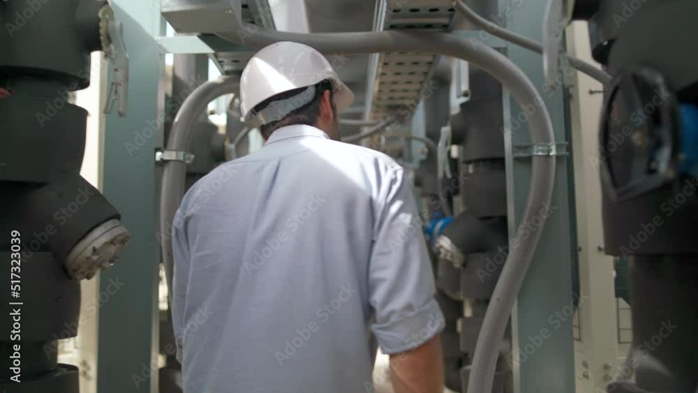 Back of engineer man walk on the way under pipe network to check the ...