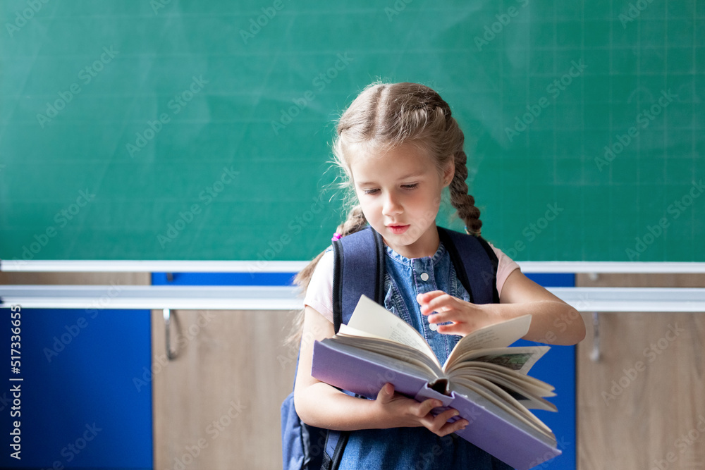 School girl reading book near chalkboard. Back to school concept. Cute ...