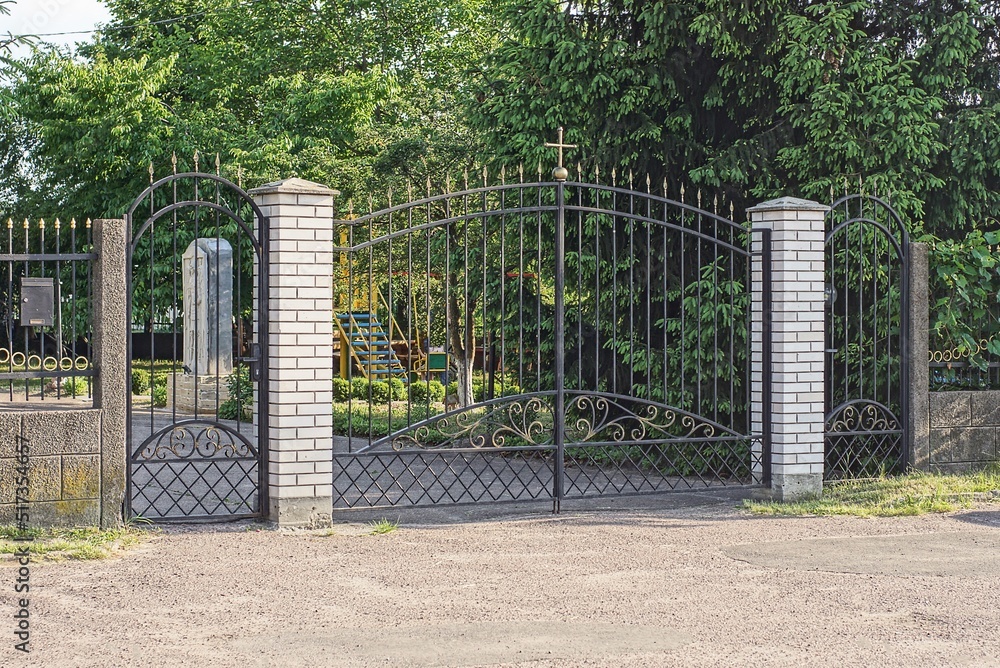 closed gate with a black forged pattern of sharp iron rods and a door ...