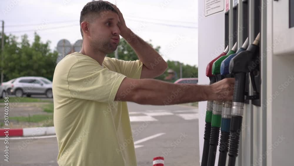 A sad angry man at a gas station is shocked by the increase in car fuel ...