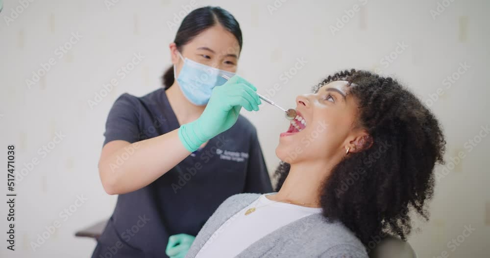 Dentist with face mask checking teeth of a female patient with a mirror ...