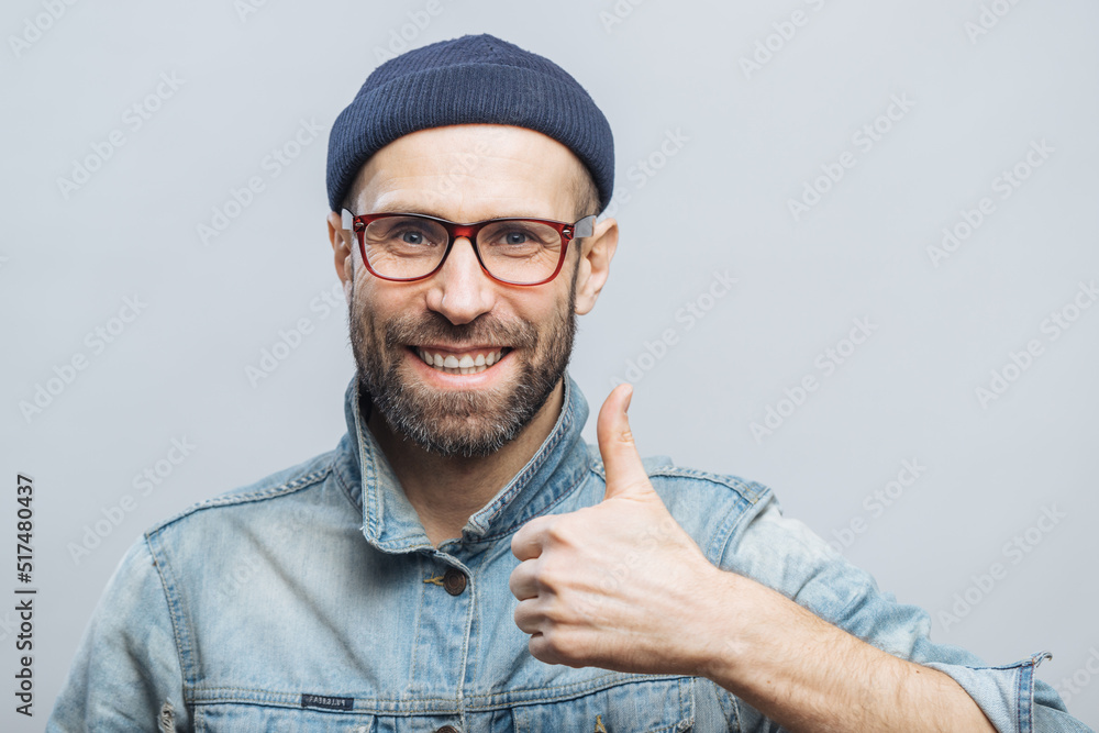 Portrait of glad middle aged male witth thick beard and mustache shows his satisfaction with ...