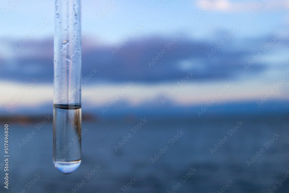 Water sample. Test tube with water. Sea and blue sky in the background ...