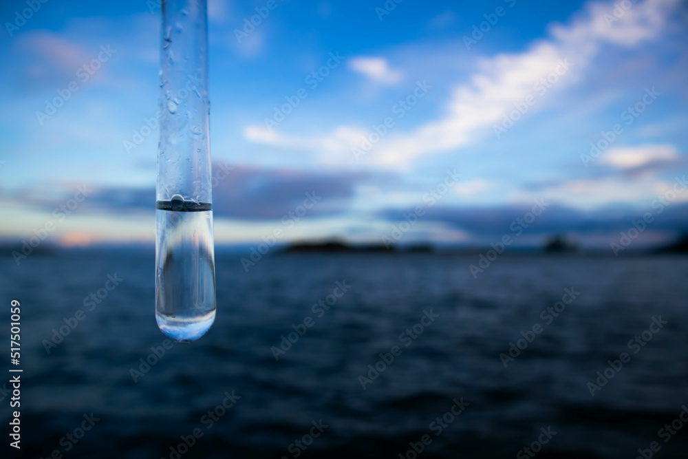 Water sample. Test tube with water. Sea and blue sky in the background ...