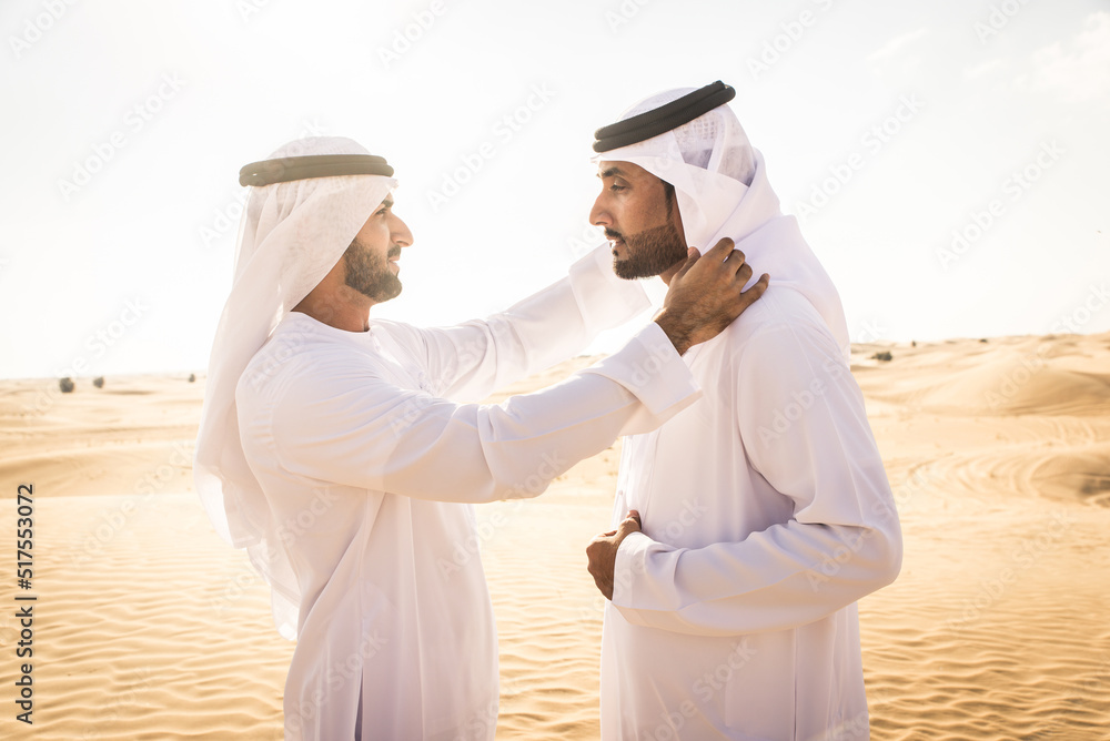 Arabic men in the desert of Dubai wearing traditional emirates clothing ...