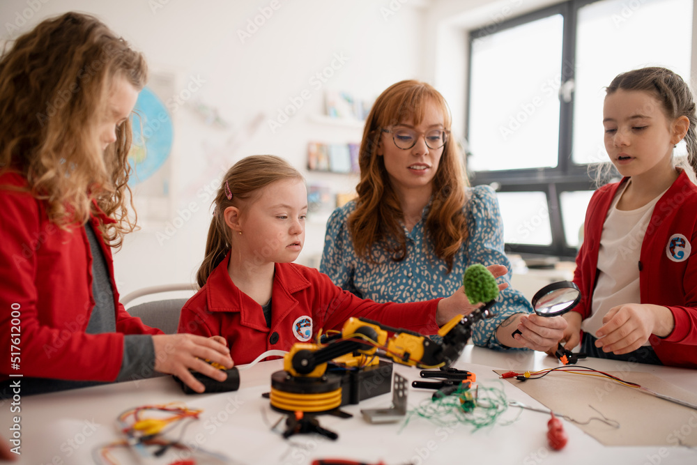 Group of kids with young science teacher programming electric toys and ...