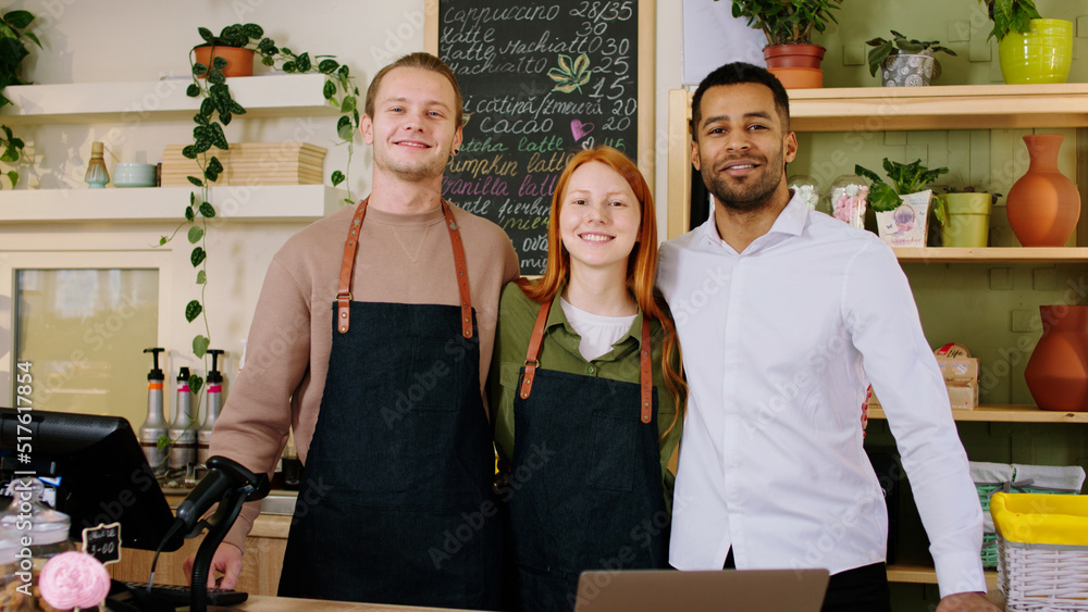 Multiethnic team in the coffee shop two baristas and the owner posing ...