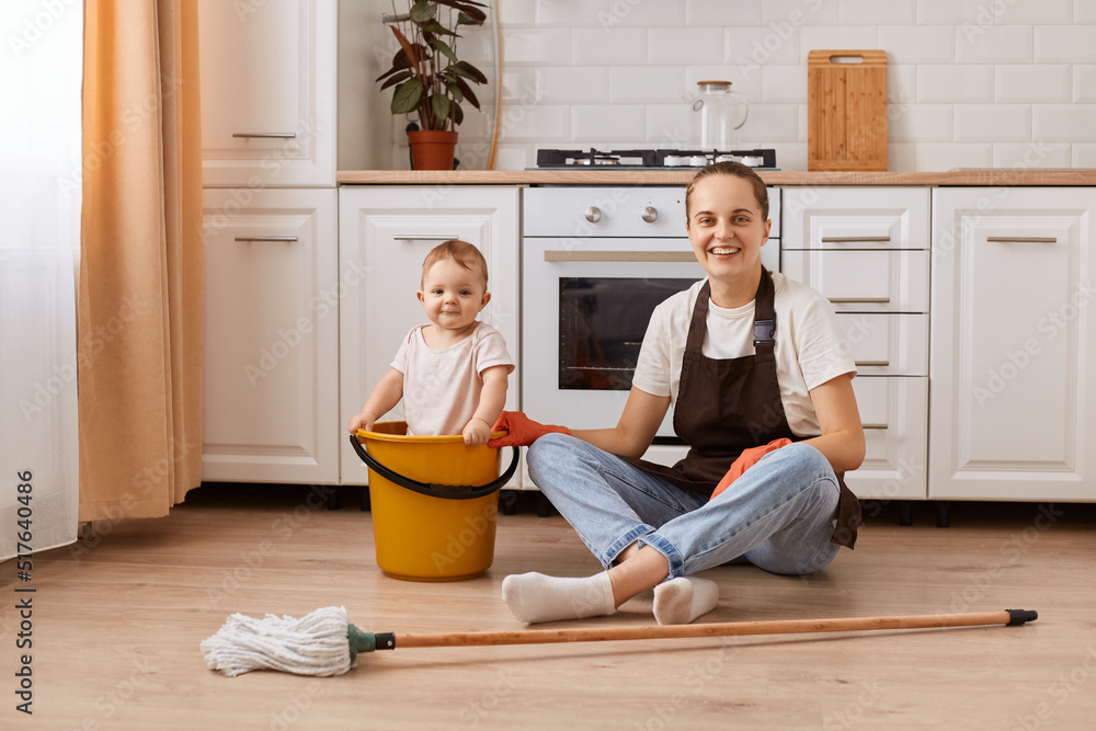 Full length photo of cute charming baby in bucket and mother housewife ...