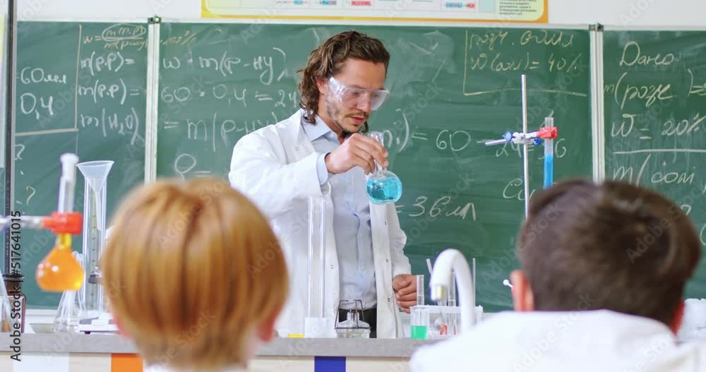 Lesson of chemistry at school. Caucasian male teacher in goggles ...