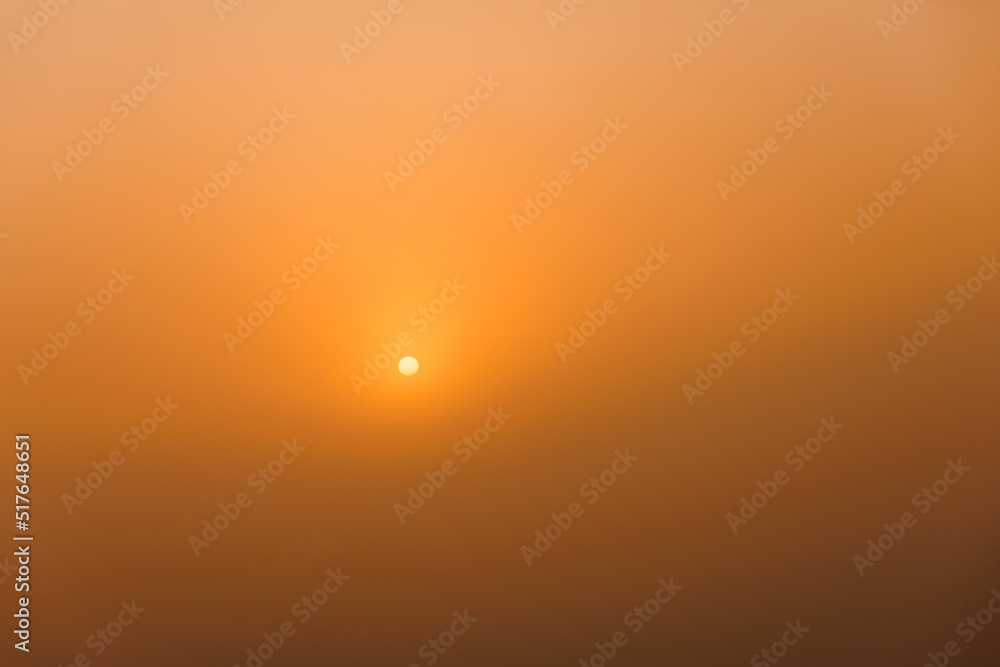 rising sun on clear golden gradient sky with visible spots in the sun ...