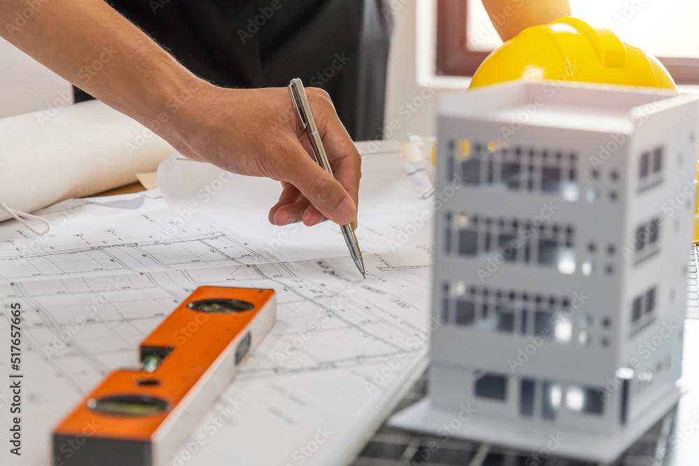 professional architect, engineer or interior hand reviewing blueprint ...