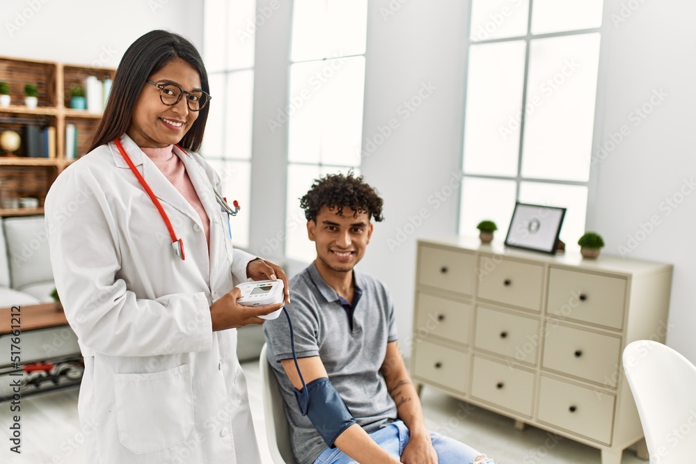 Young latin doctor woman smiling happy measuring pulse using ...