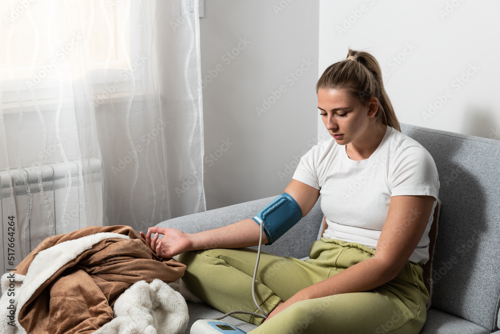 Young sick woman or girl measures her blood pressure with a digital ...