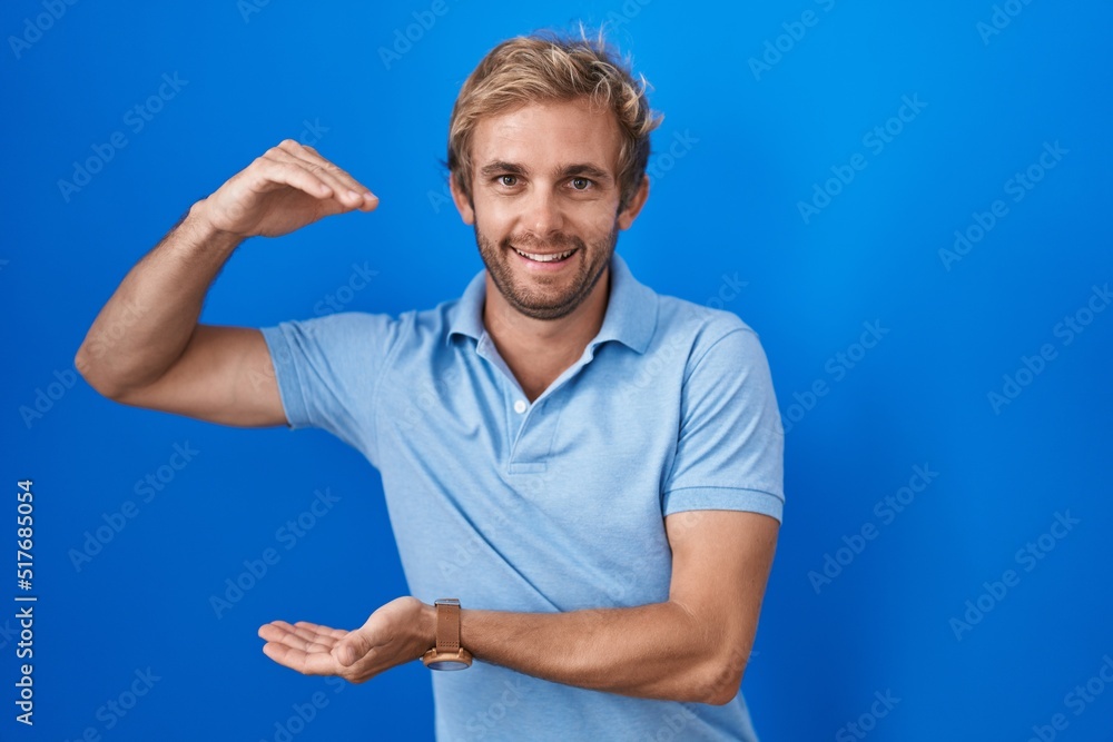 Caucasian man standing over blue background gesturing with hands ...