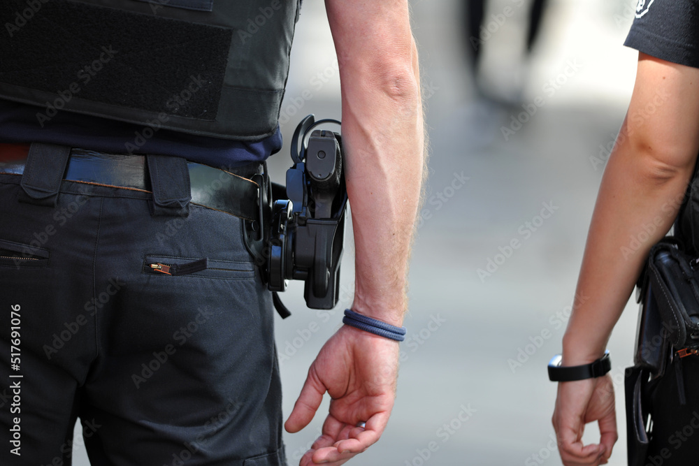 Partial view of a male and a female police officer walking on patrol in ...