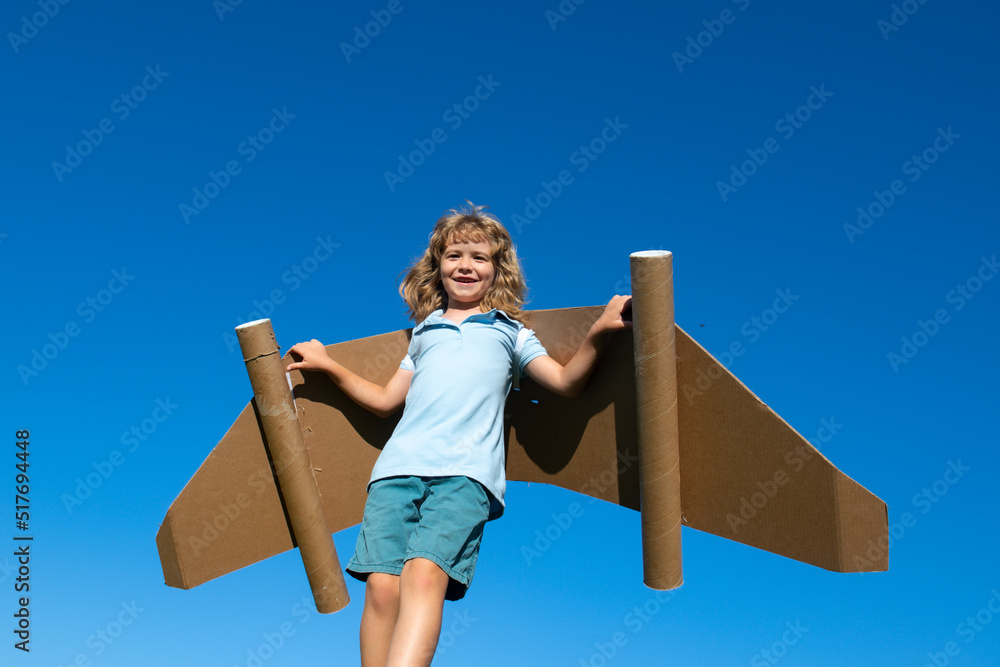 Kid with toy jetpack outdoor. Child playing on sky with cardboard wings ...