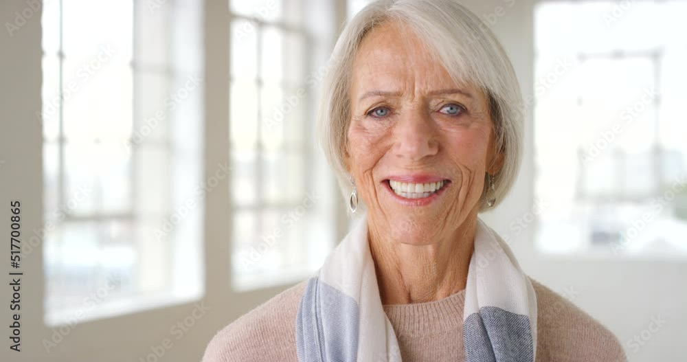 Portrait of a senior woman laughing inside a bright building with copy ...