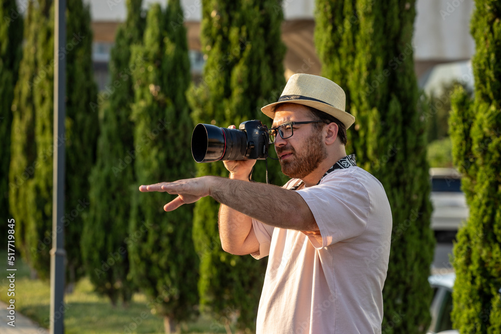 photographer on the photoshoot in hat at park with camera professional ...