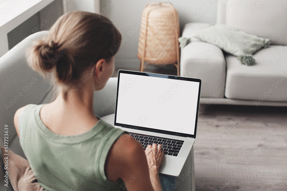 Young woman using laptop computer with white mockup screen at home ...