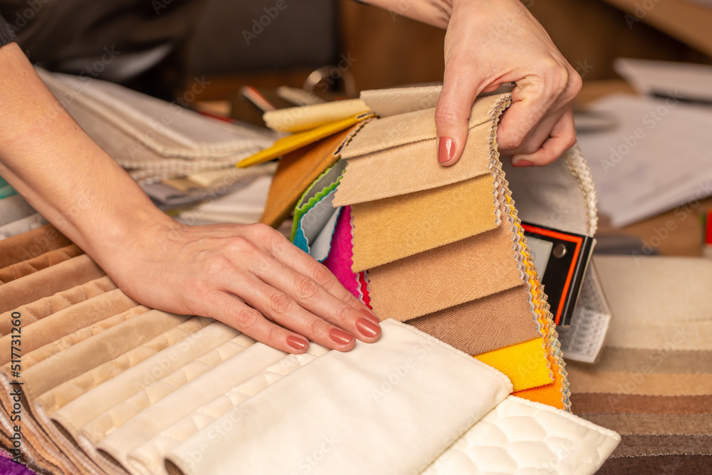 Fabric swatches in different colors are stacked for selection. A woman ...