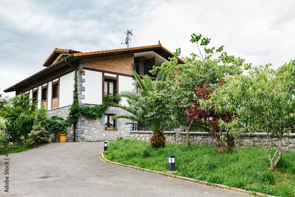 Lush green trees growing near rural cottage with balconies under cloudy ...