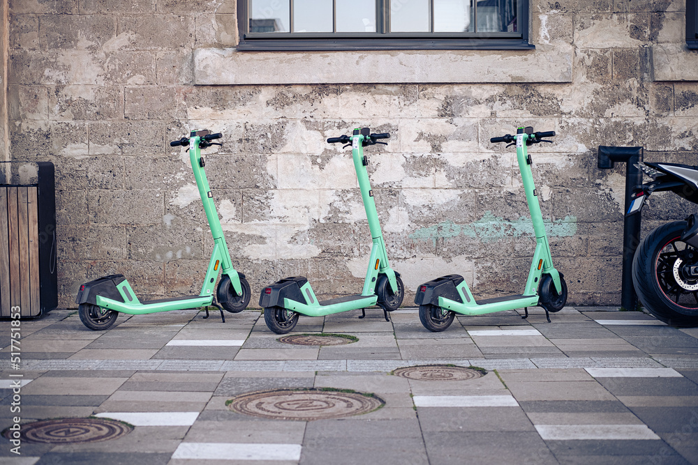 Electric scooters standing on the street in the park zone with house ...