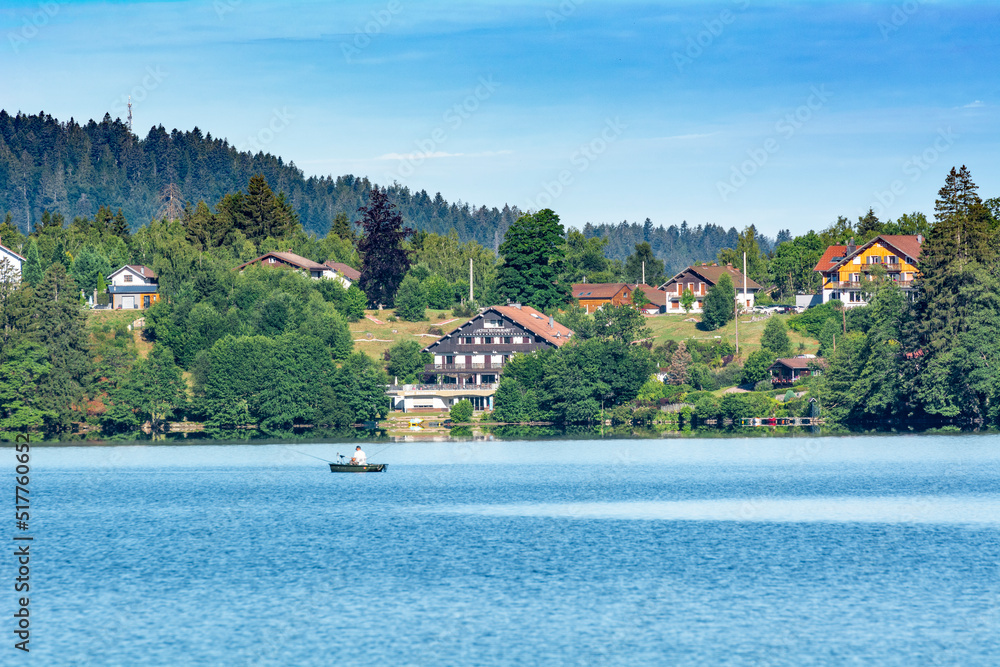 Hotels de montagne et pécheur dans une barque sur les bords du lac de ...