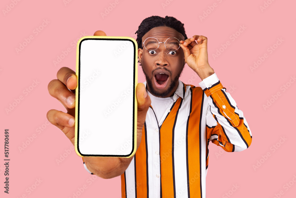 Surprised shocked bearded a man holding his eyeglasses, showing screen ...