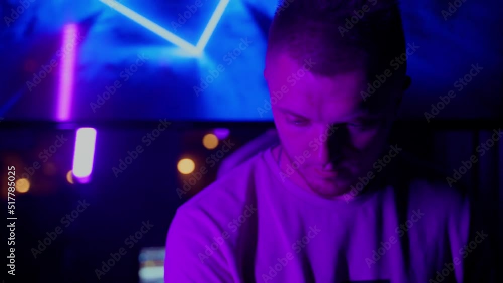 DJ in club working indoors in neon lights close up. Caucasian male ...