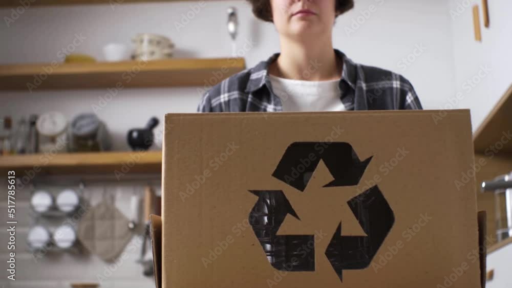 Woman in kitchen covers plastic bottles with a cardboard box with a ...